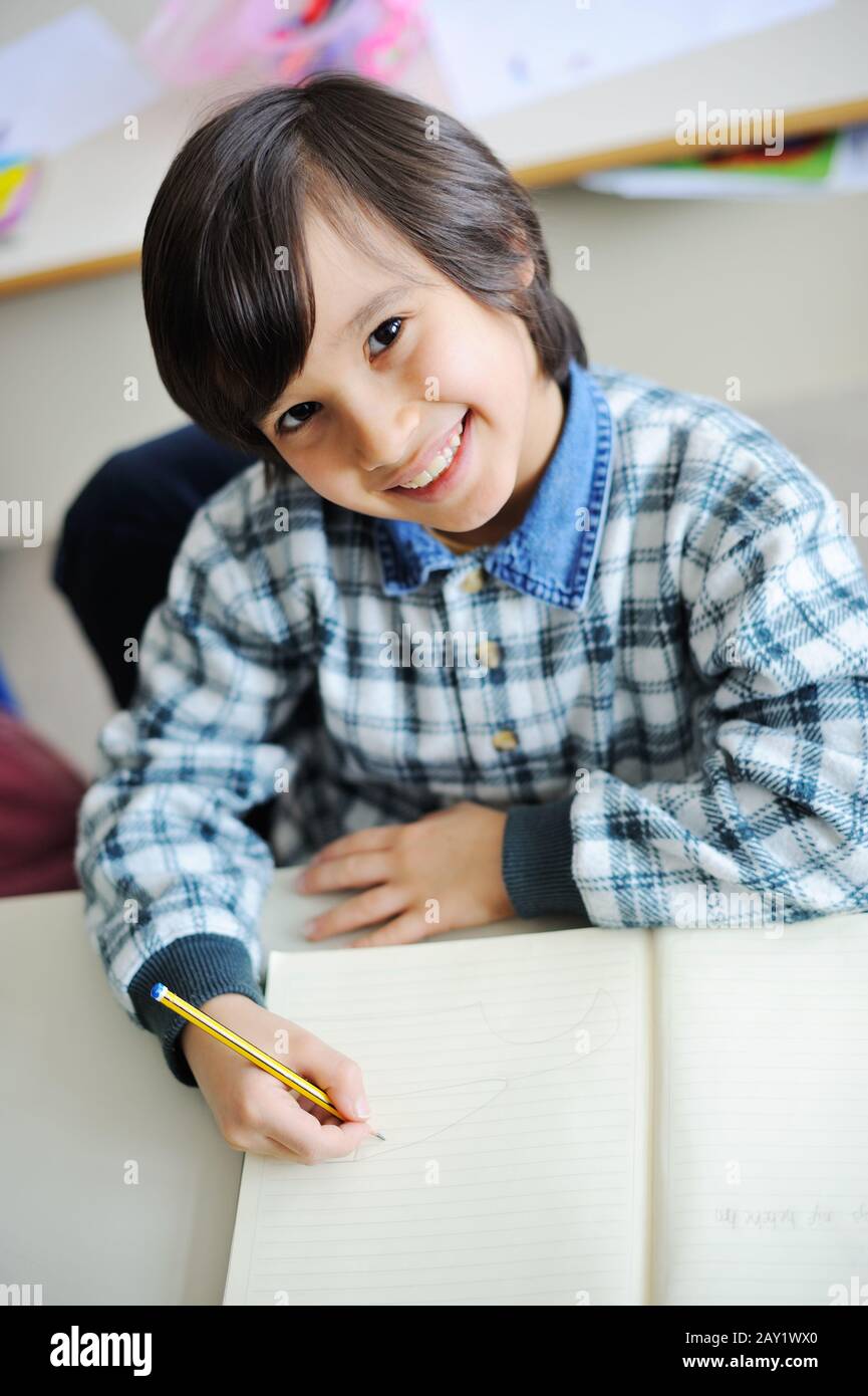 Happy student writing in notebook in school classroom Stock Photo - Alamy