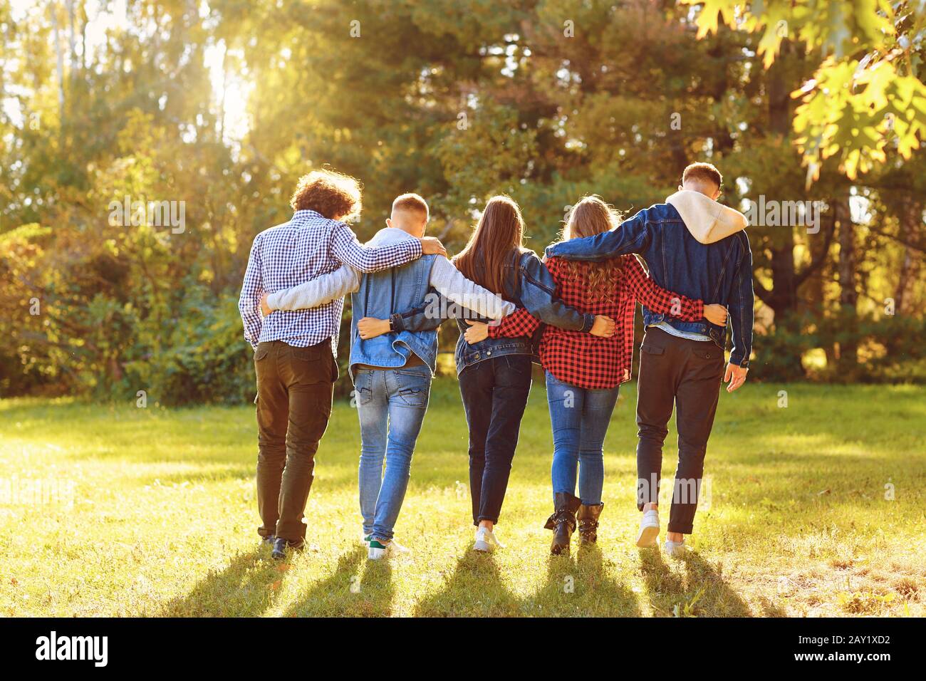 Embracing friends walking together in park Stock Photo - Alamy