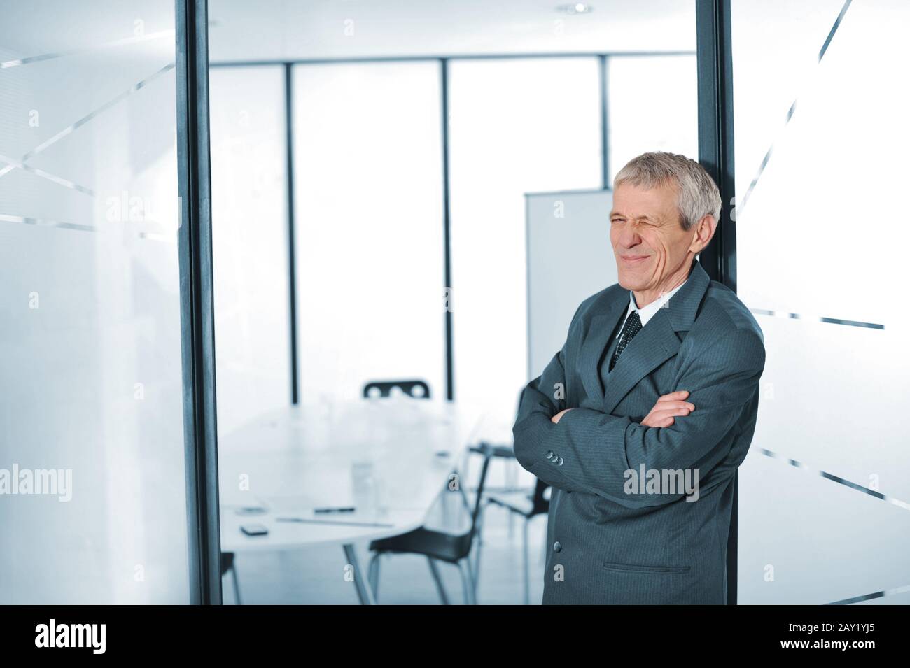 Elderly business man winking with folded arms Stock Photo - Alamy