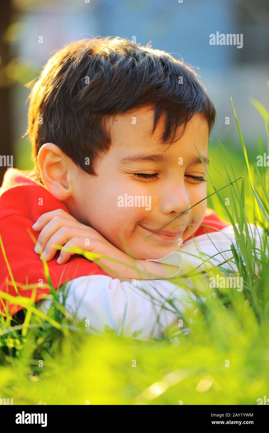 Little cute boy laying on morning summer grass with natural beautiful ...