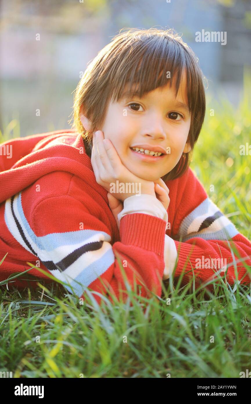Little cute boy laying on morning summer grass with natural beautiful ...