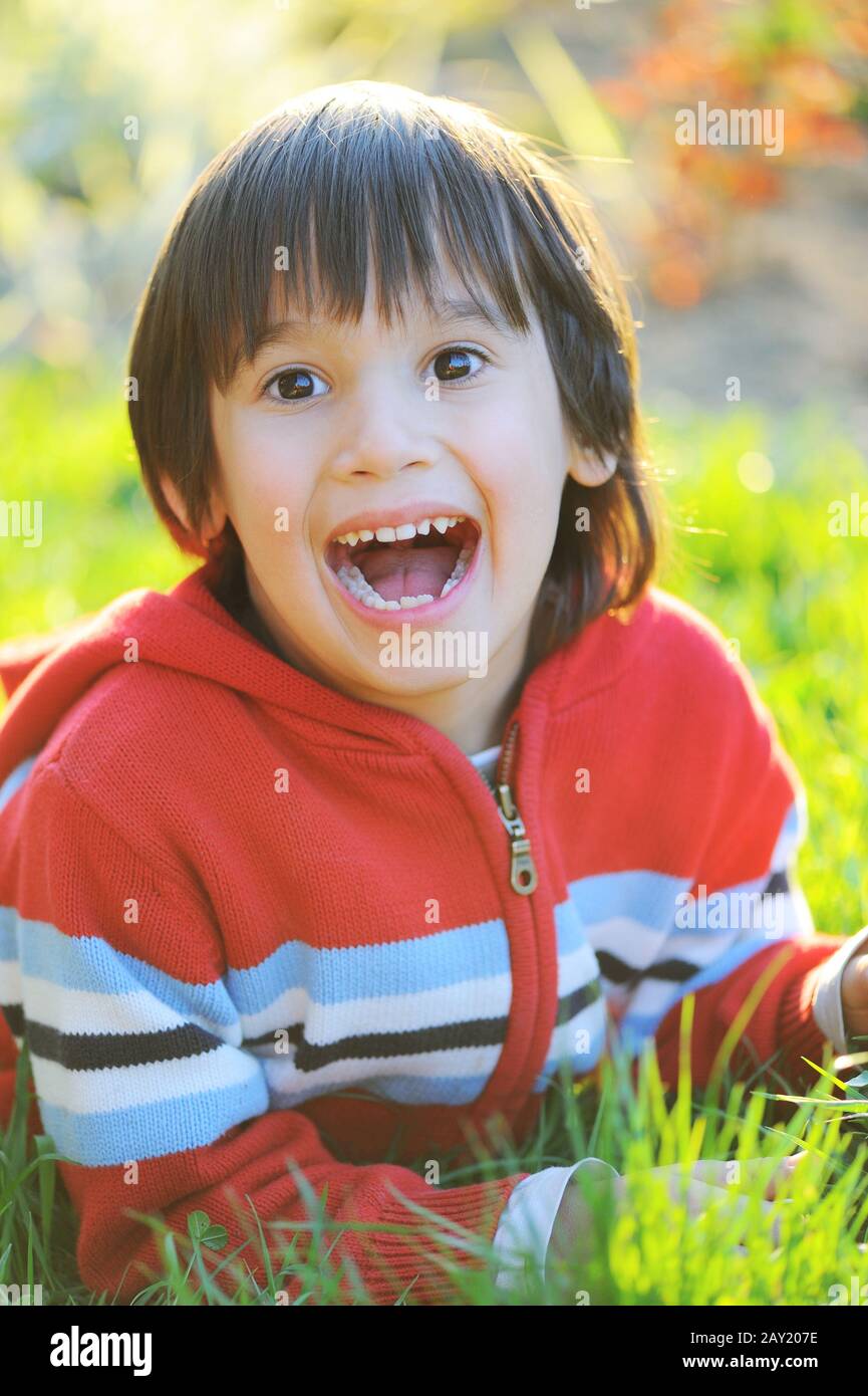 Little cute boy laying on morning summer grass with natural beautiful ...