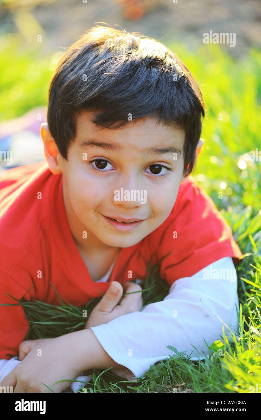 Little cute boy laying on morning summer grass with natural beautiful ...