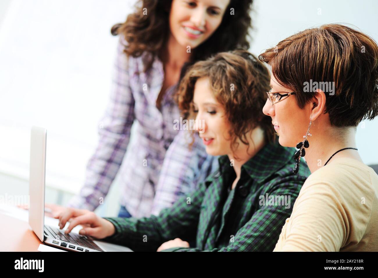 Group of young happy people looking into laptop working on it Stock ...