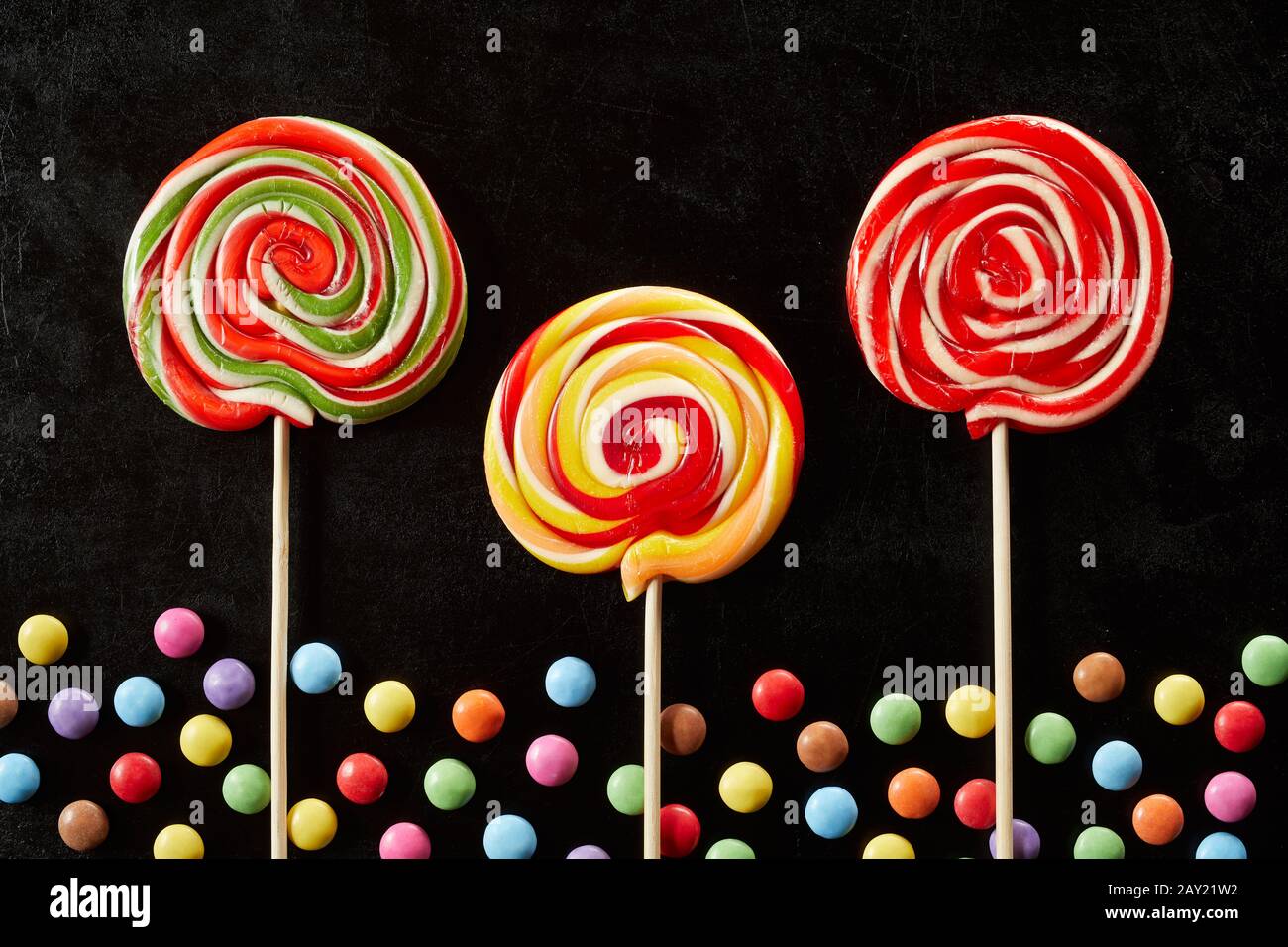 Three brightly colored red, green and yellow lollipops with a border of ...