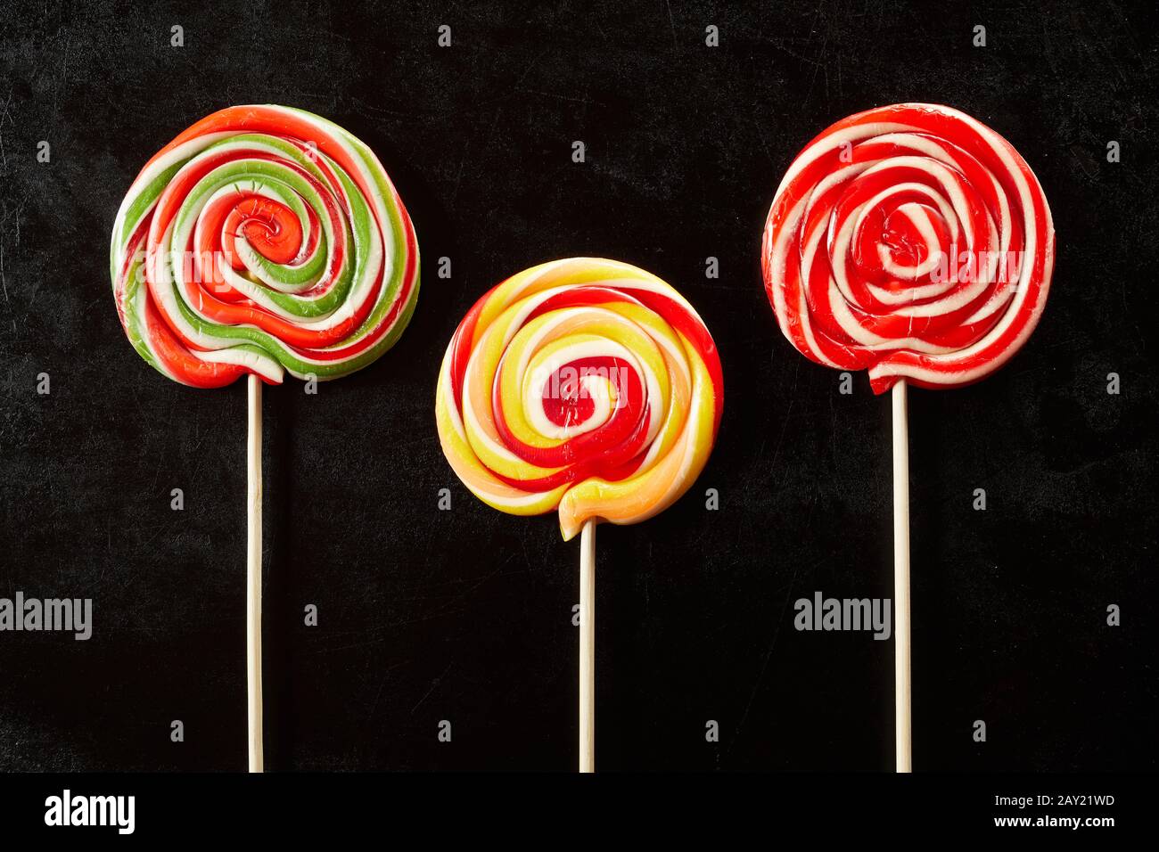 Three colorful red based lollipops on a black background in a neat ...