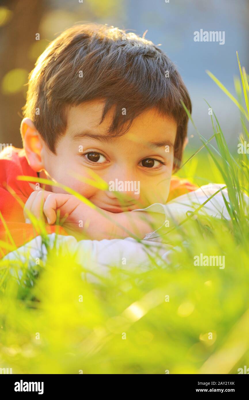 Little cute boy laying on morning summer grass with natural beautiful ...