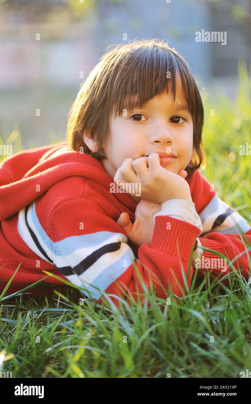 Little cute boy laying on morning summer grass with natural beautiful ...