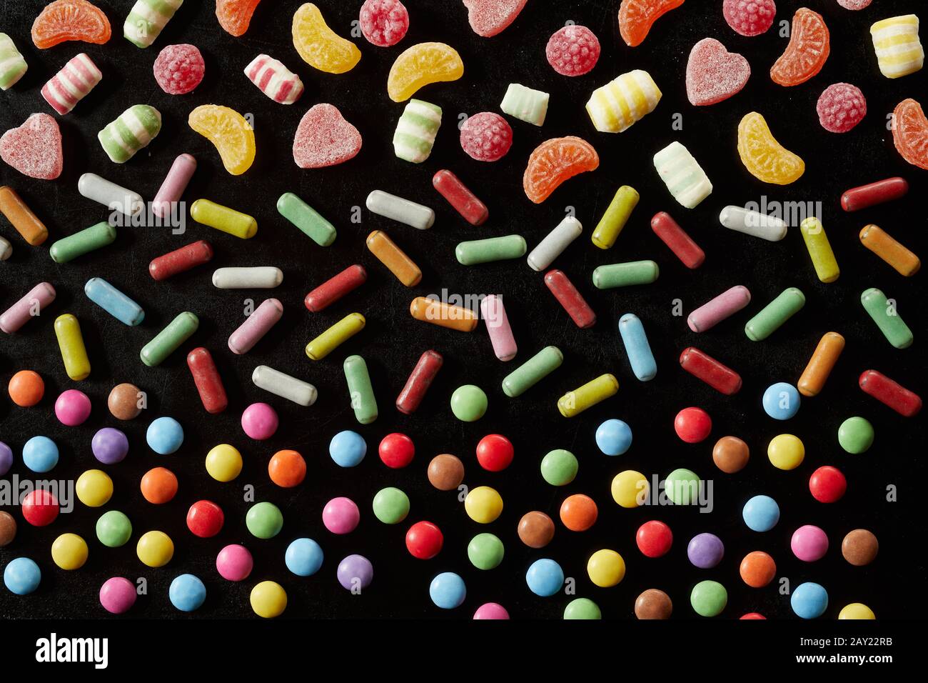 Rainbow colored assorted sweets on a black background with sugar-coated ...