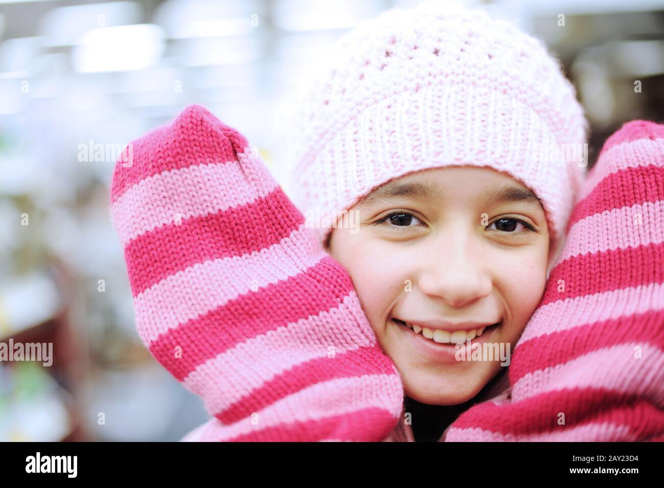 Portrait of a beautiful smiling girl wearing winter hat and gloves ...
