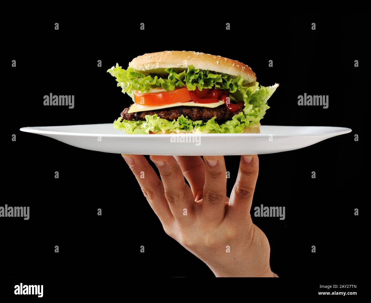 Hamburger in hand on plate Stock Photo - Alamy