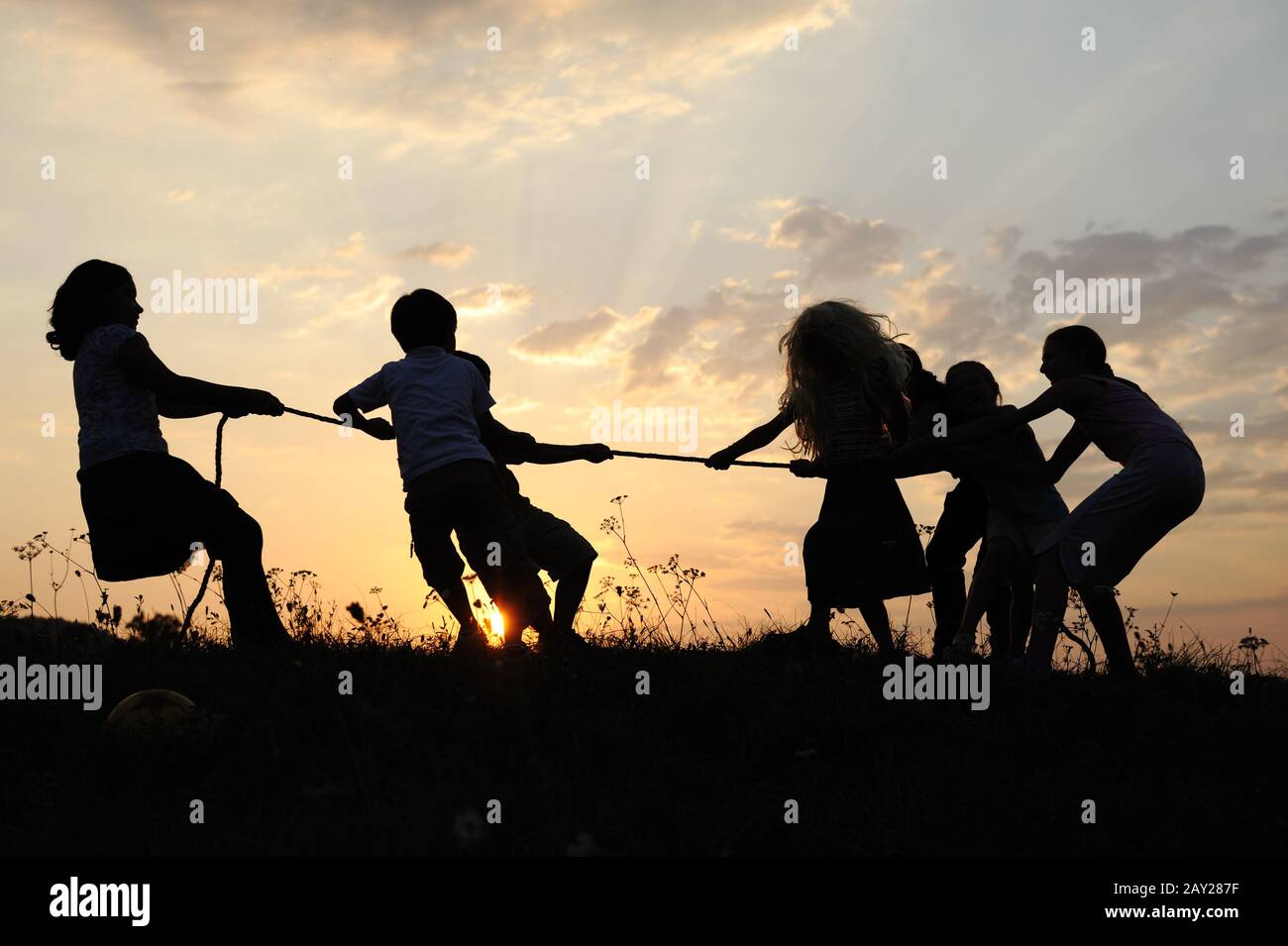 Silhouette, group of happy children playing on meadow, sunset ...