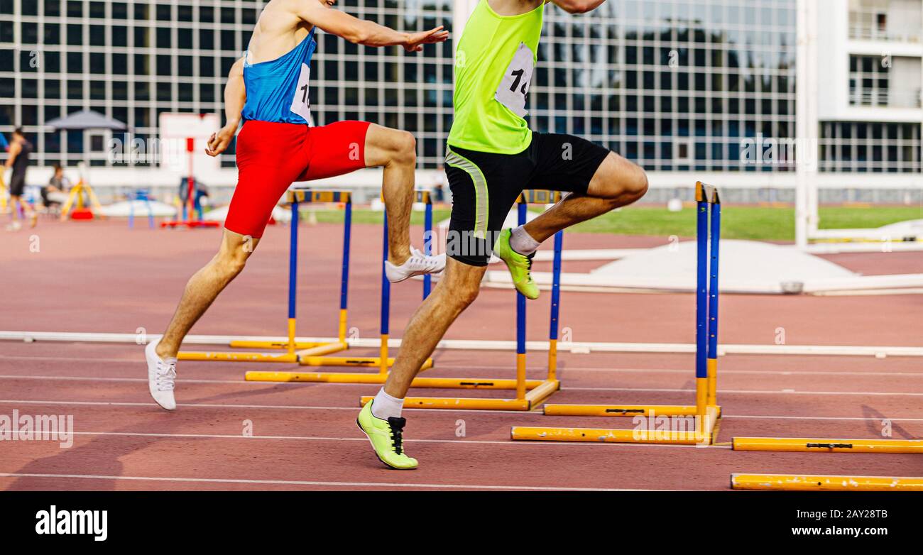 male athletes run hurdles at stadium in athletics competition Stock ...