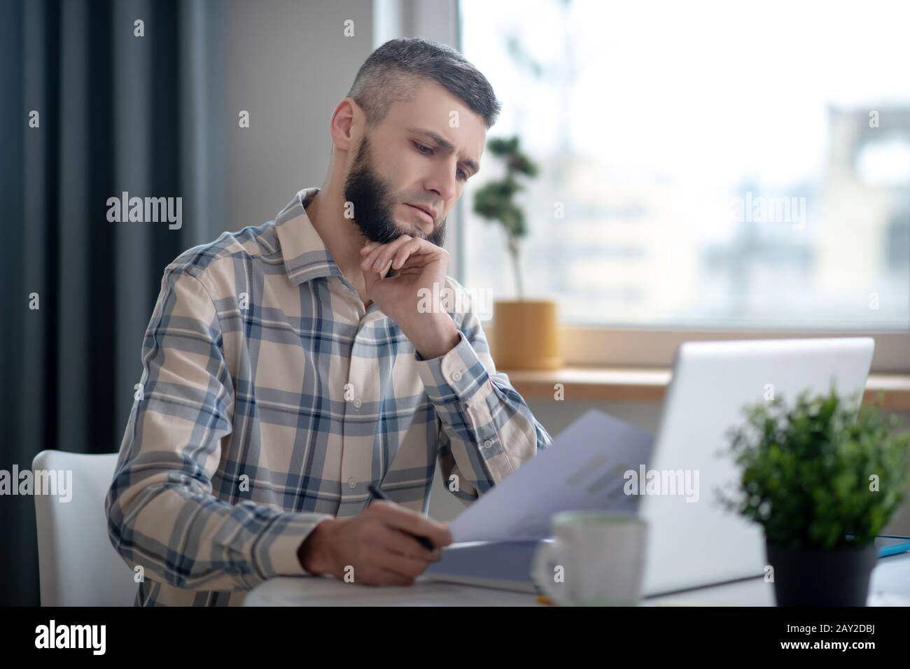 Young man sitting at a table and looking at a chart Stock Photo - Alamy