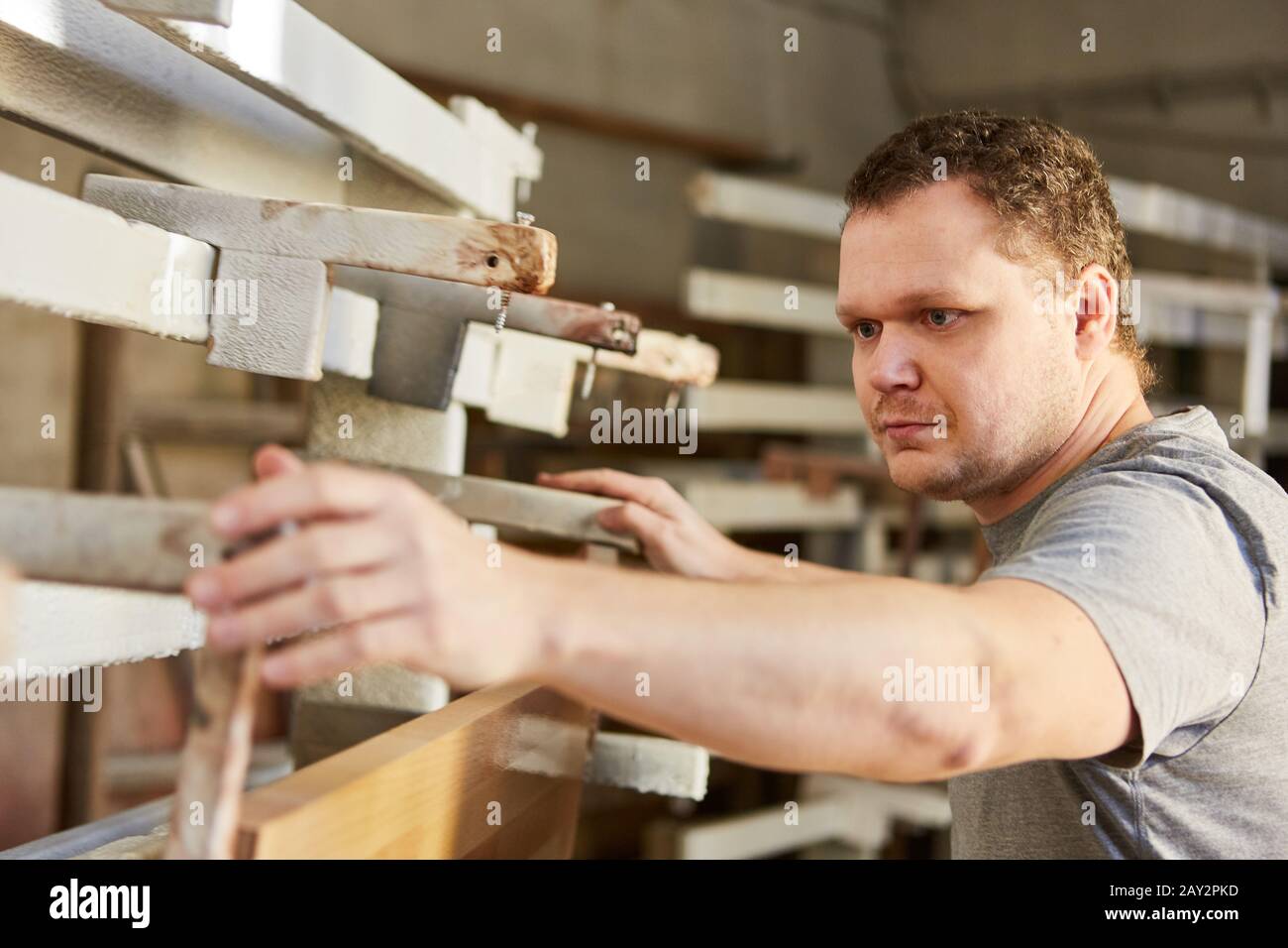 Young carpenter as a furniture maker gluing wood in the carpentry ...