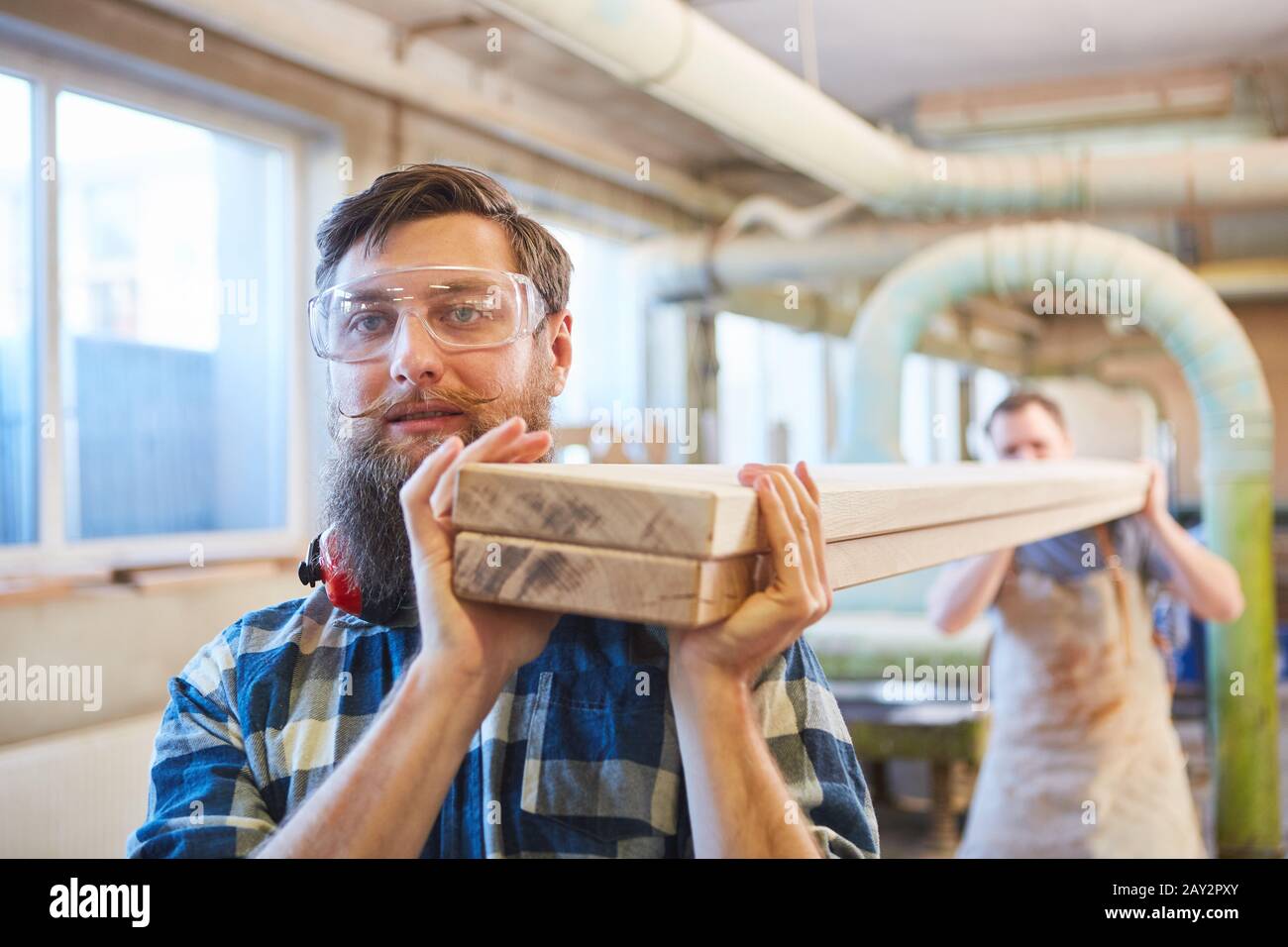 Carpenter apprentices carry wooden beams in the carpentry workshop ...