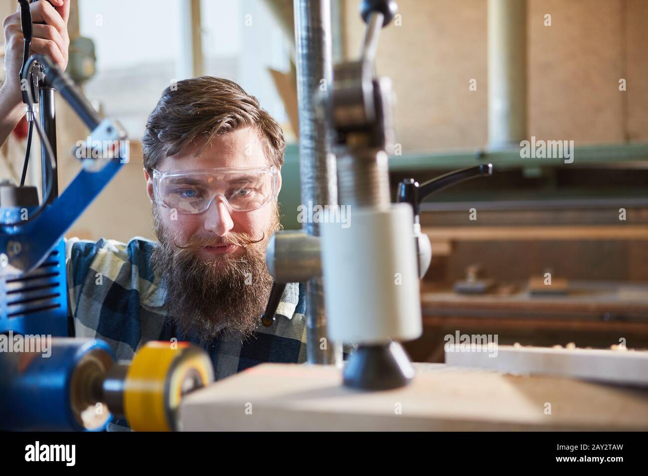 Hipster carpenter operates a drill with laser display in the carpentry ...
