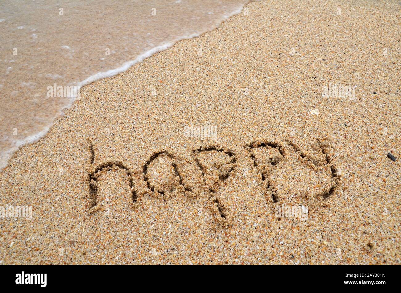 Happy word written on sandy the beach Stock Photo - Alamy