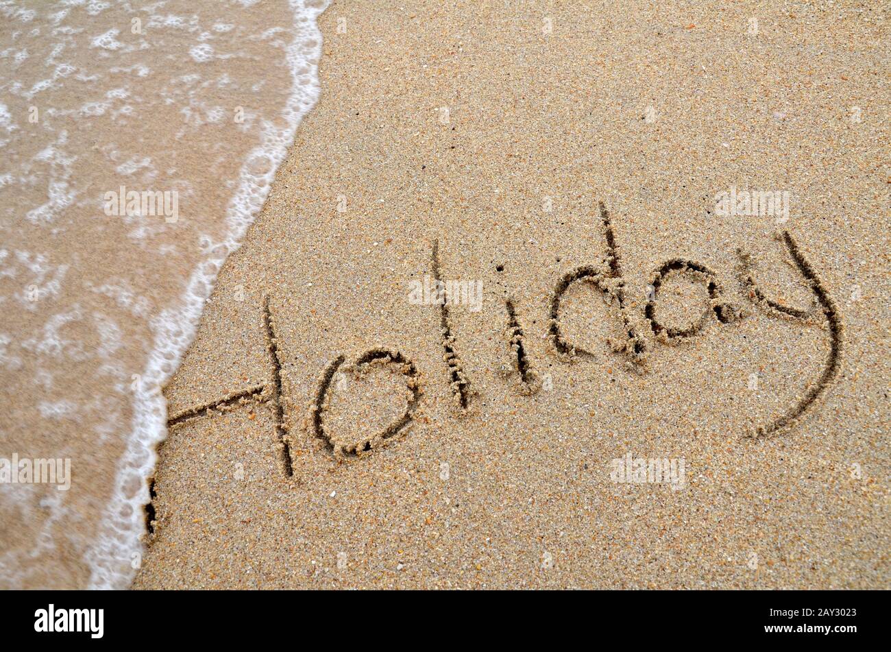 Holiday word written on sandy beach Stock Photo - Alamy