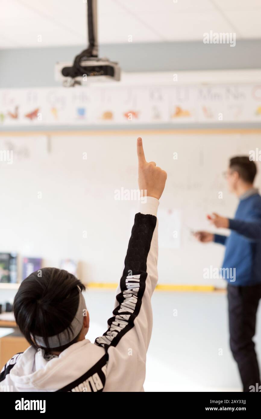 Boy raising hand in classroom hi-res stock photography and images - Alamy