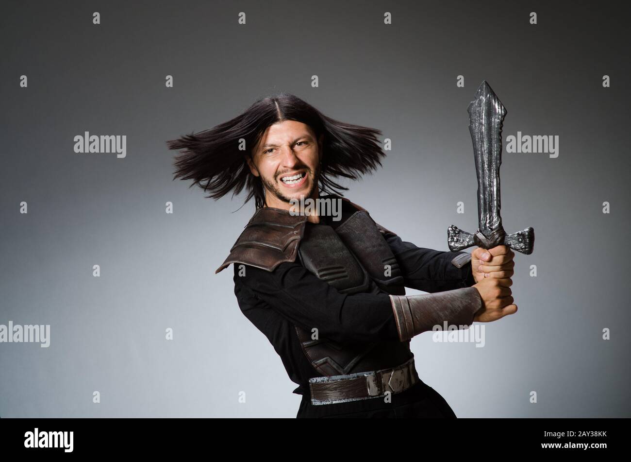 Angry knight with sword against dark background Stock Photo - Alamy