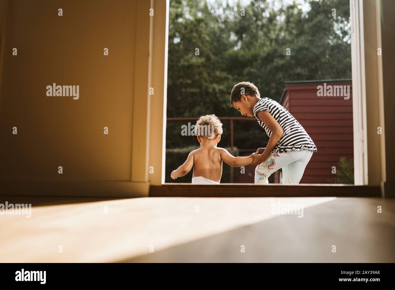 Siblings seen through open door Stock Photo - Alamy