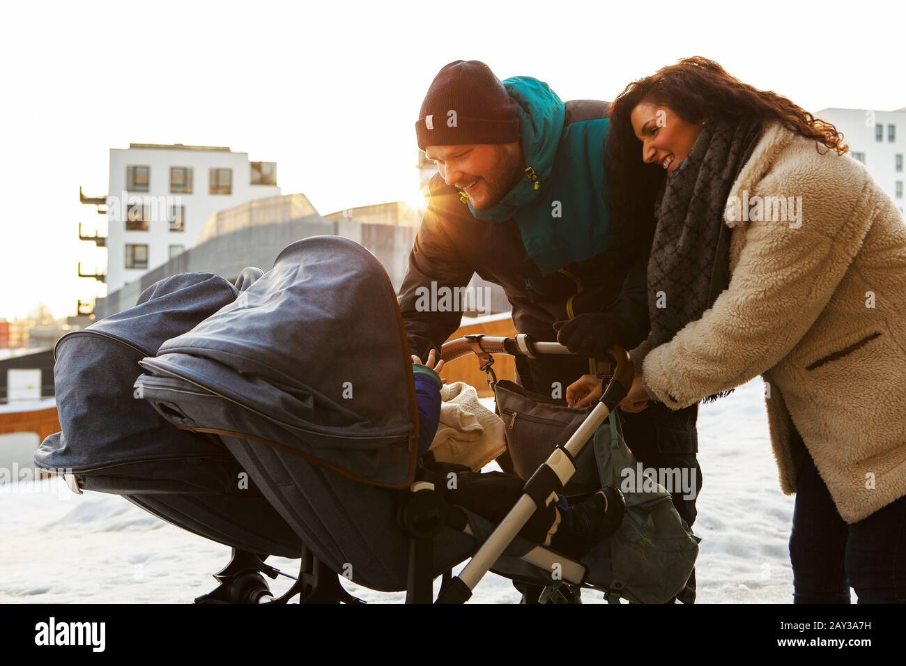 Parents looking inside pram Stock Photo - Alamy