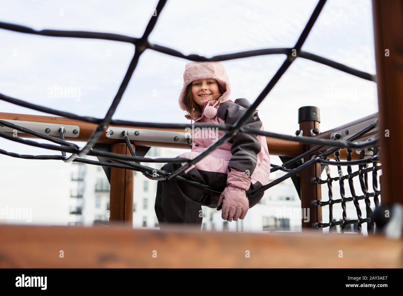 Smiling girl sitting on climbing frame Stock Photo - Alamy