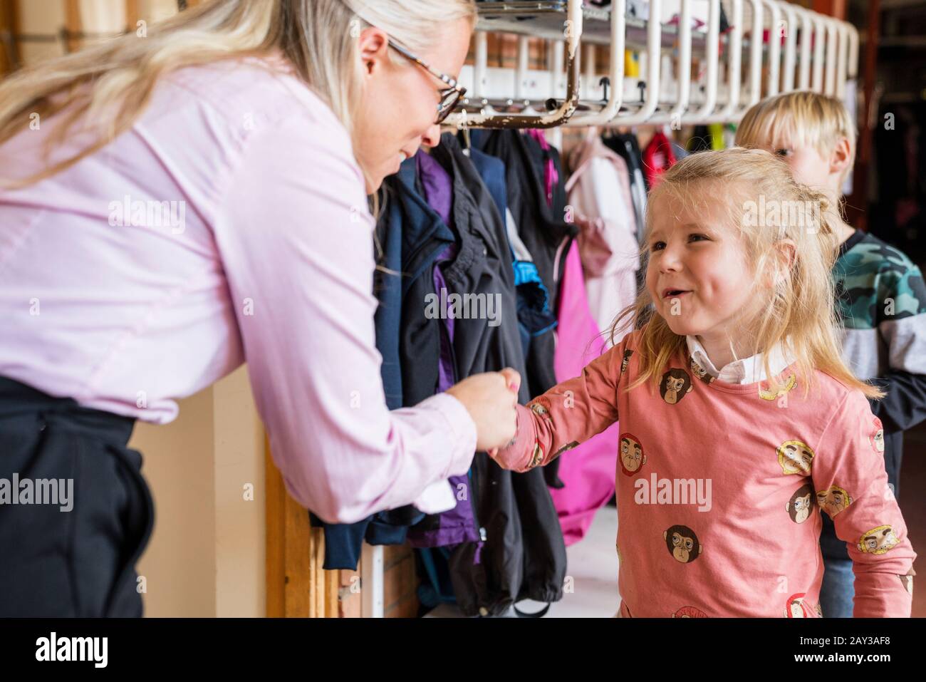 Teacher greeting children Stock Photo - Alamy