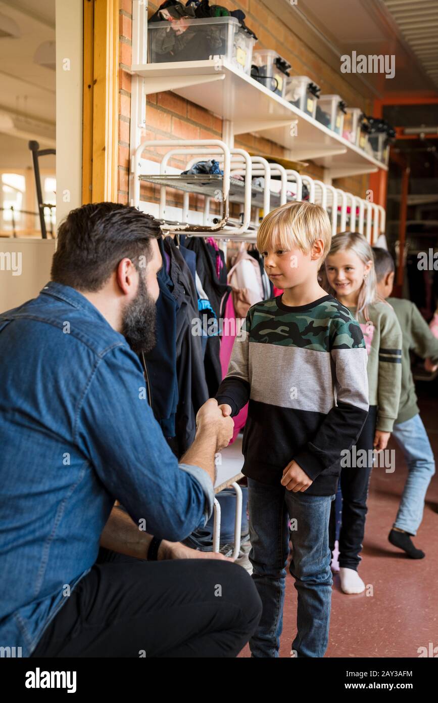 Teacher greeting children Stock Photo - Alamy