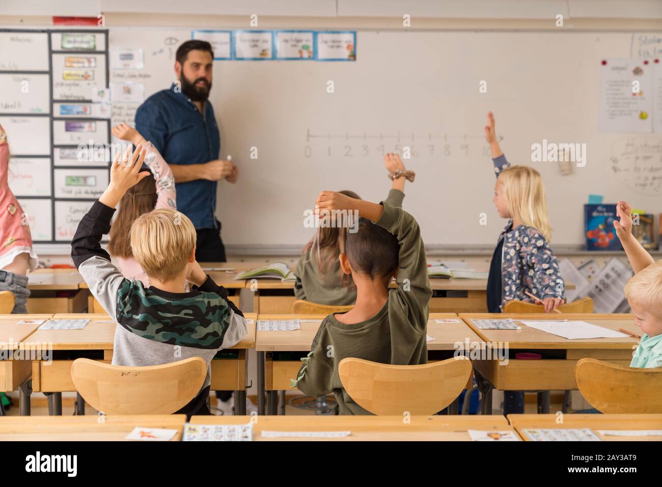 Children raising hands classroom Stock Photo - Alamy