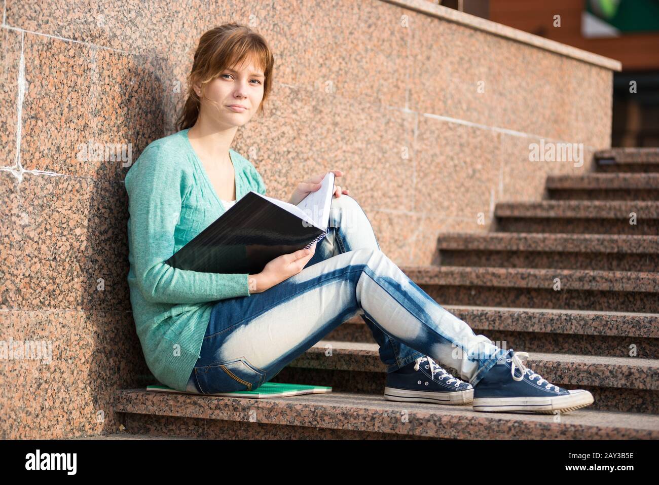Girl sitting on stairs and reading note Stock Photo - Alamy
