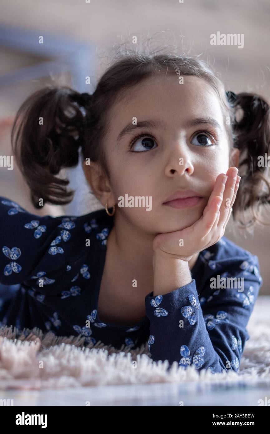 Middle Eastern young cute girl lies on a light bed in the light of ...