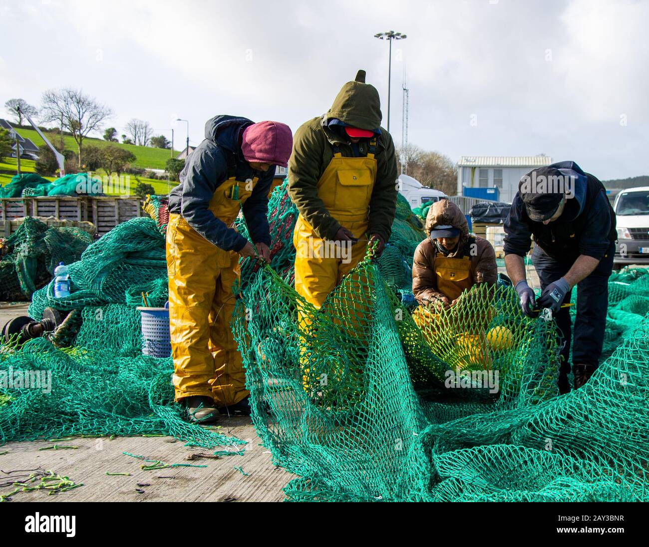 4 fishermen mending nets in union hall harbour ireland Stock Photo - Alamy