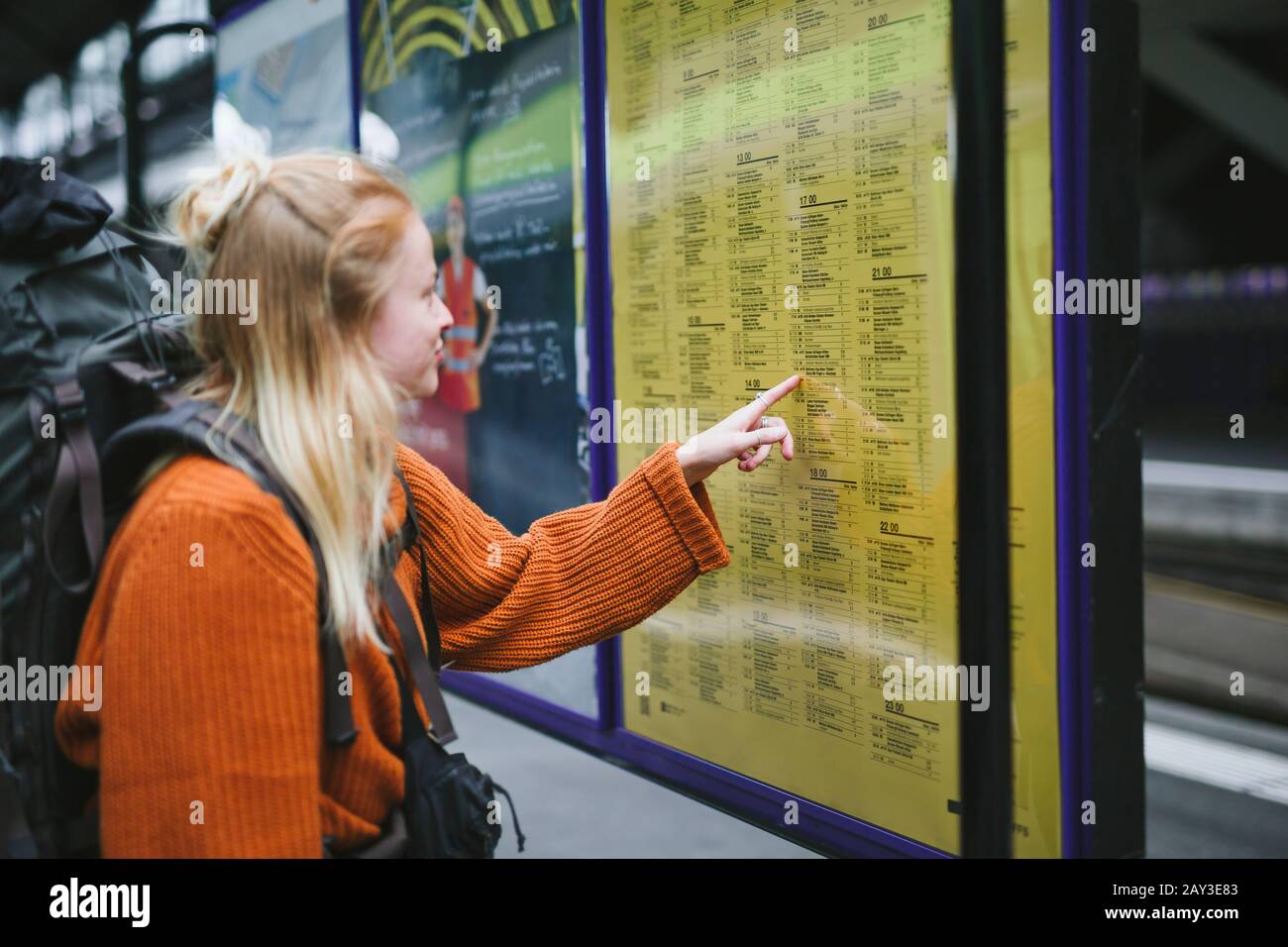 Woman on train station checking timetable Stock Photo - Alamy
