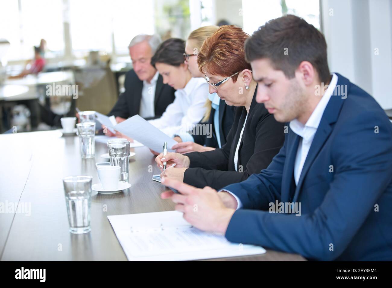 Businesspeople sit together at the table in the conference room during ...