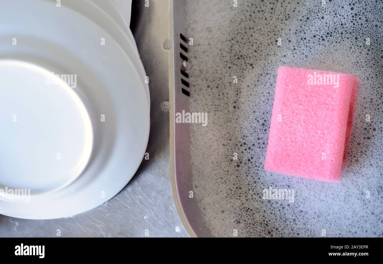 Sink with a colorful pink sponge and clean dishes Stock Photo - Alamy