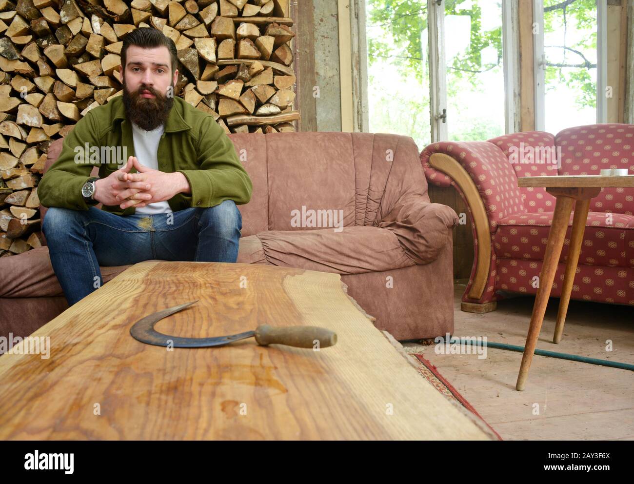 Men with beard sitting on a couch with an sickle on the table Stock ...
