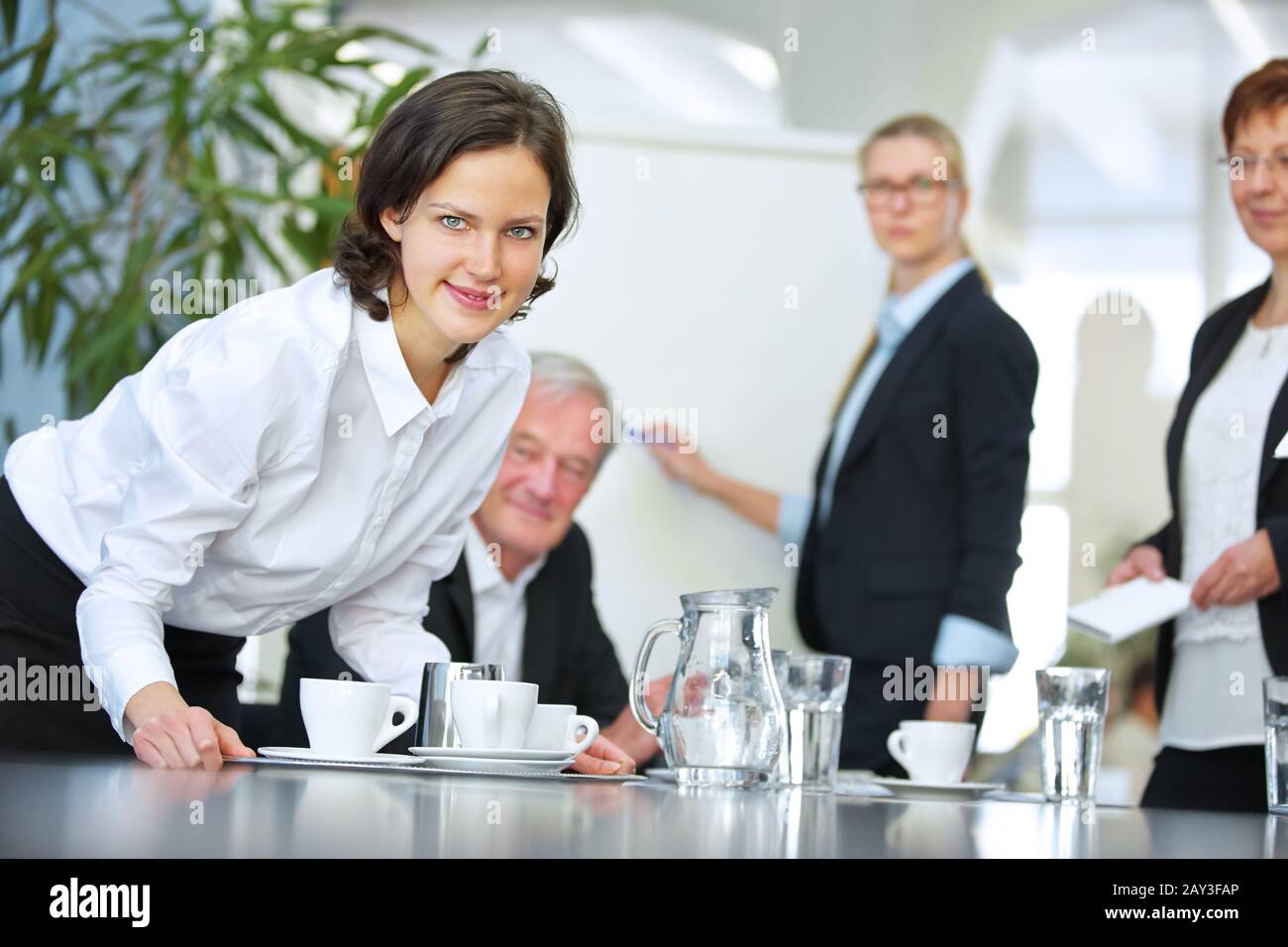 Assistant brings coffee and water to a business meeting Stock Photo - Alamy