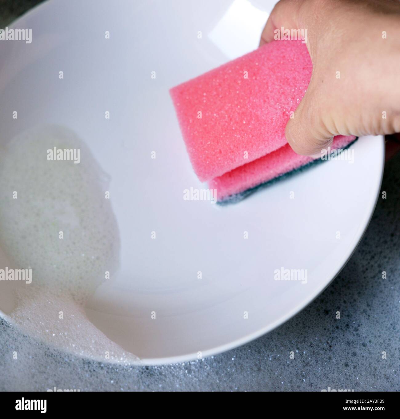 Clean the dish with water and a pink sponge Stock Photo - Alamy