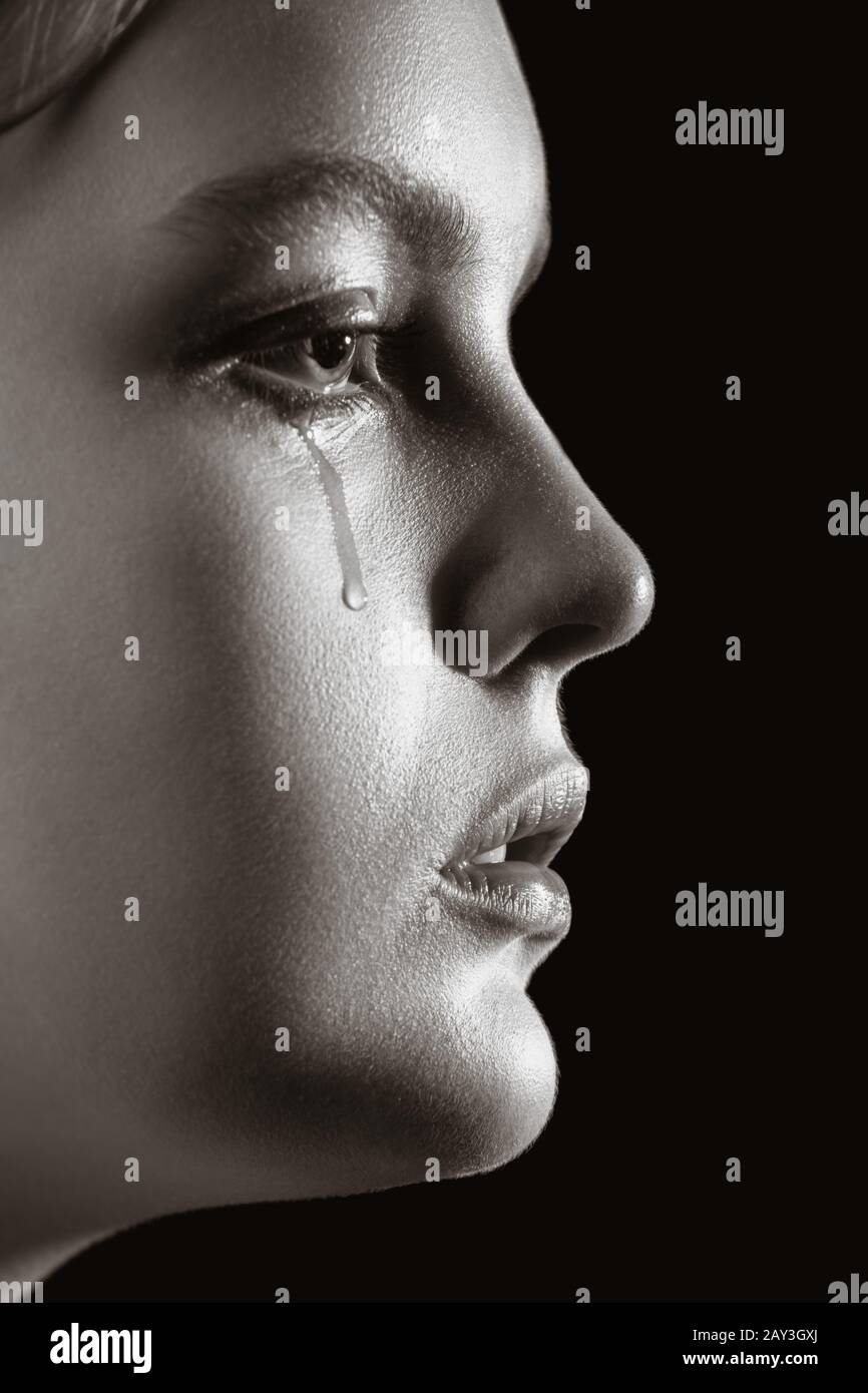 sad woman crying, looking aside on black background, closeup portrait ...