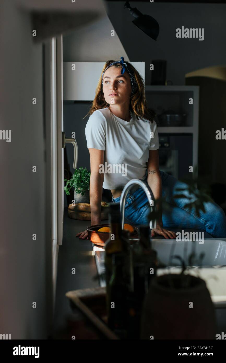 Woman looking through kitchen window Stock Photo - Alamy