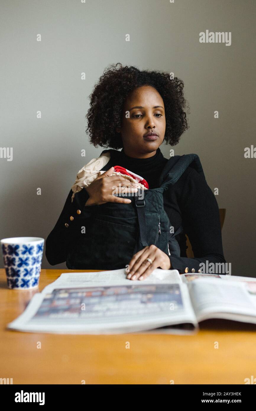 Woman with baby reading newspaper Stock Photo - Alamy