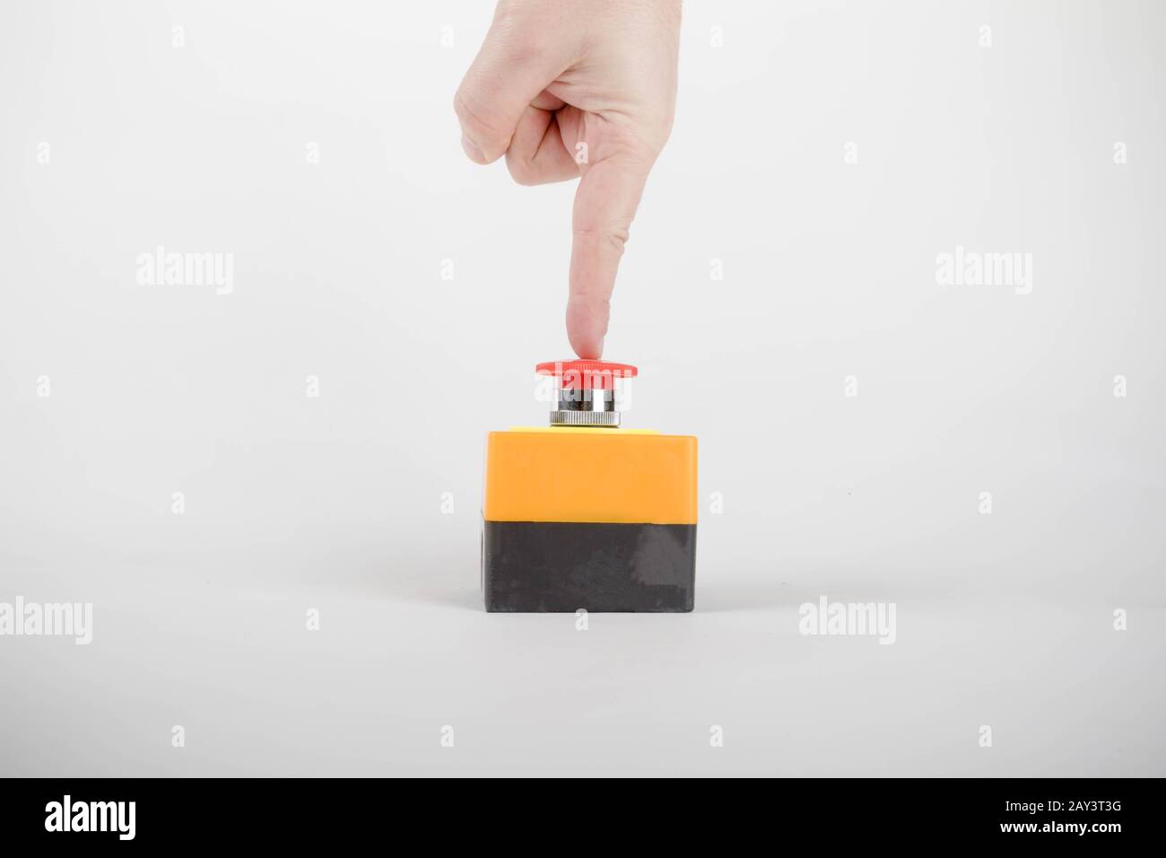 An industrial emergency stop button with a finger pressing down Stock ...