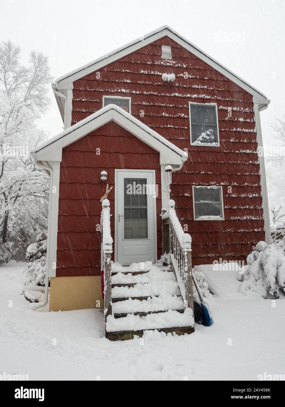 red suburban house in the snow on a grey winter stormy day Stock Photo ...