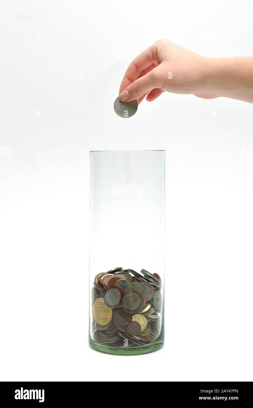 dropping coin into glass jar Stock Photo - Alamy