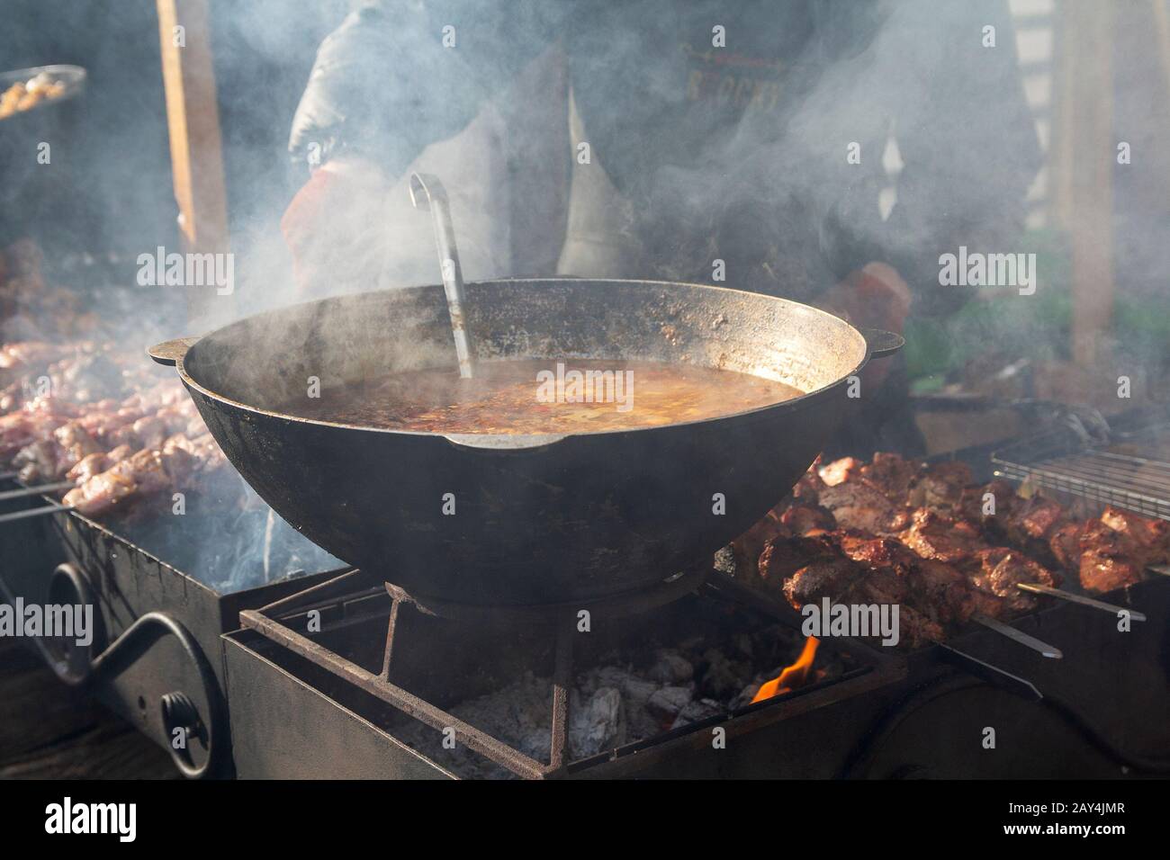 Metal pot over a fire on the street food festival Stock Photo - Alamy