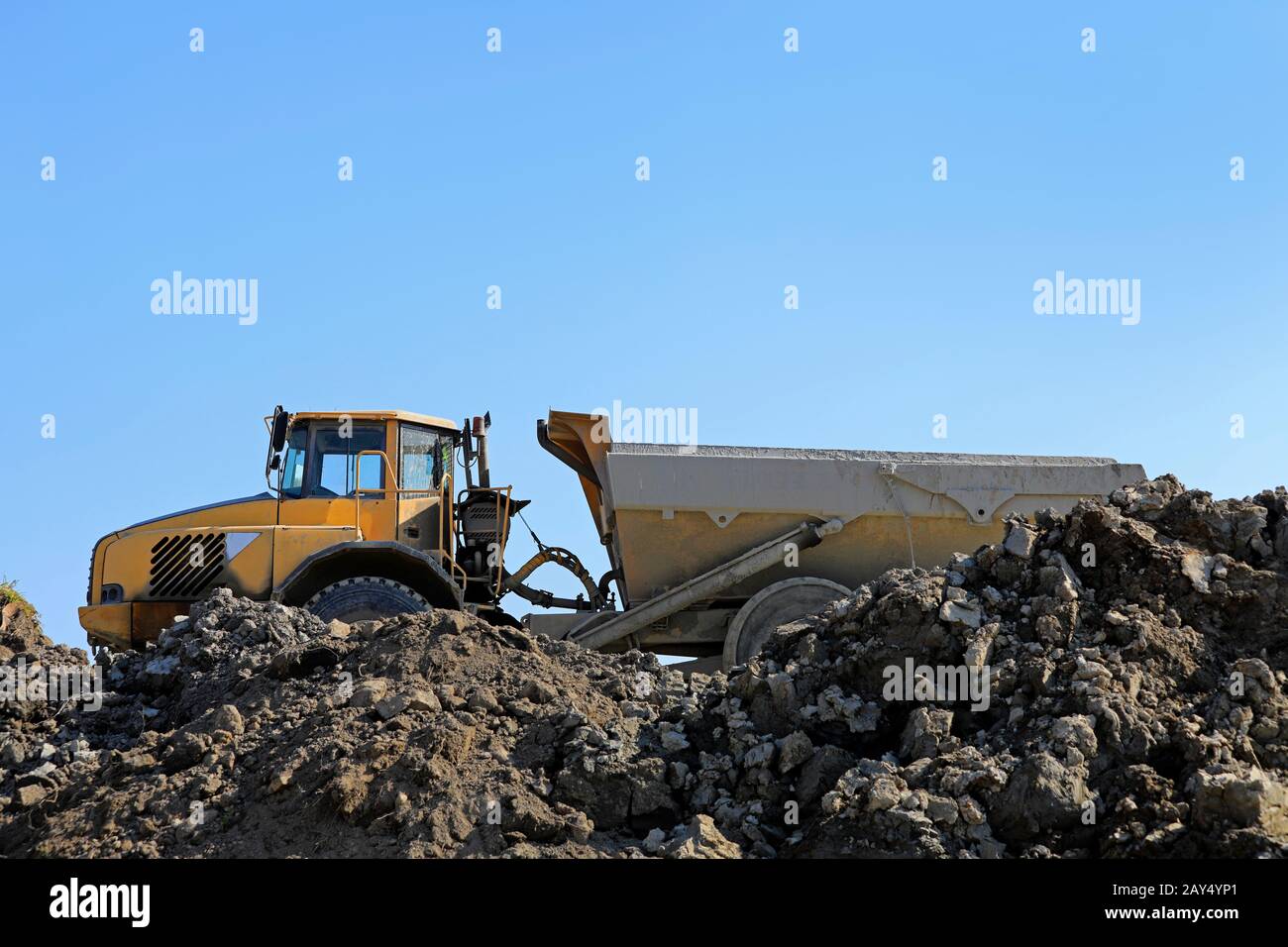 Yellow articulated hauler at road construction site, blue sky with copy ...
