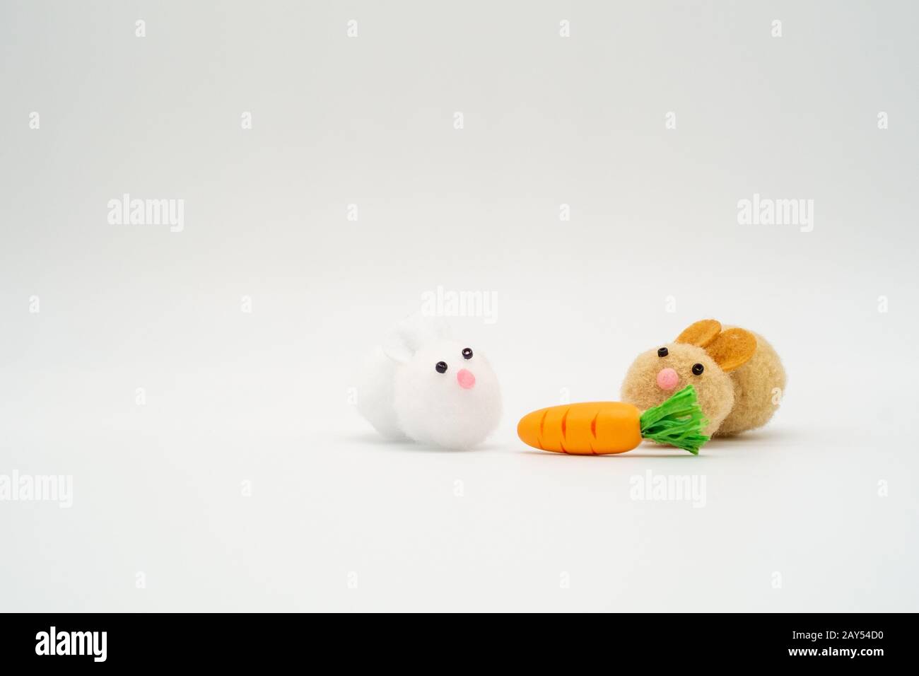 Two cute brown and white rabbit pom pom toys with carrot isolate Stock ...
