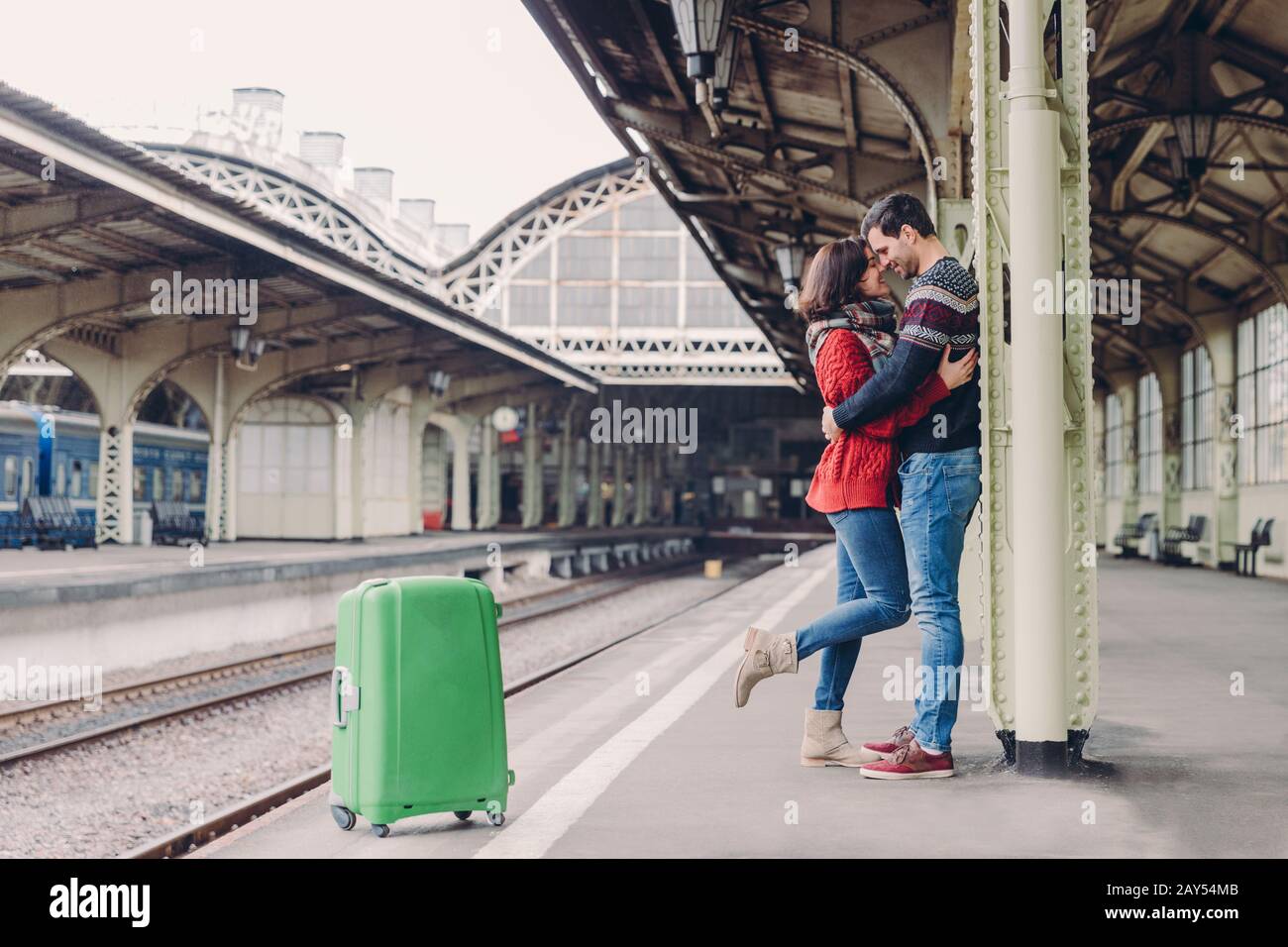 Shot of lovely boyfriend and girlfriend stand closely, embrace and kiss ...